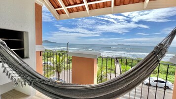 Uma rede em uma varanda com vista para o oceano, oferecendo uma visão clara do mar e da terra ao longe.