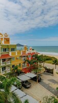Um hotel à beira-mar com edifícios coloridos, vista para a praia e área de estacionamento.