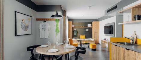 Uma cozinha moderna com área de refeições, armários de madeira e uma televisão.