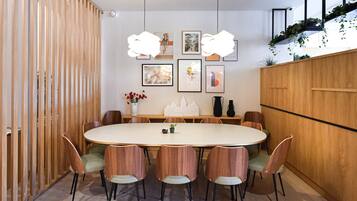 Uma sala de jantar com uma mesa redonda, cadeiras de madeira e luminárias pendentes.
