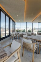 Um terraço amplo no terraço com várias áreas de estar, grandes janelas que oferecem vistas panorâmicas da cidade e um design de teto moderno.