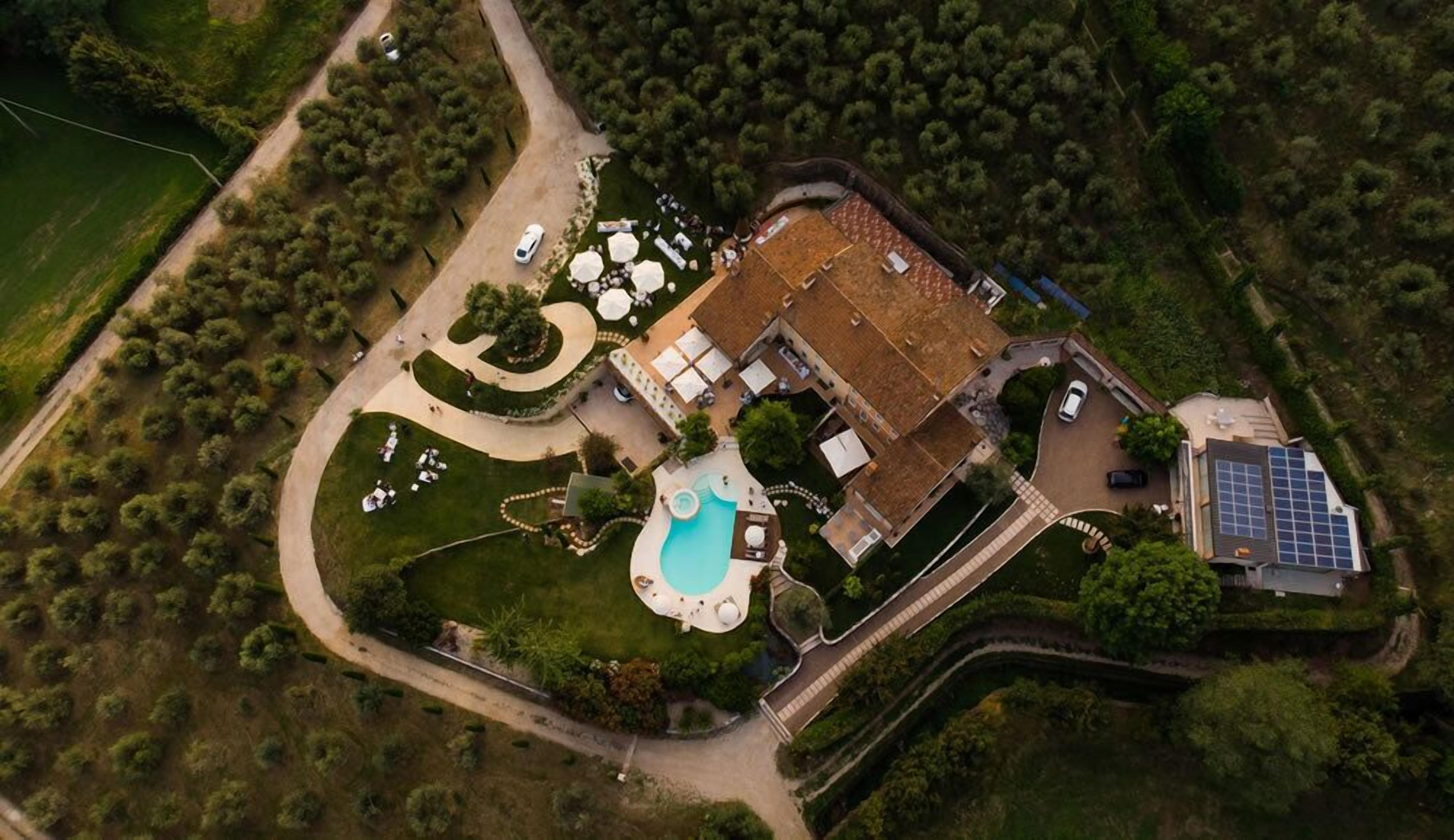 Vista aérea de uma propriedade com piscina, varanda coberta e instalação de painéis solares.