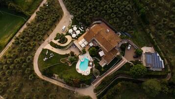 Vista aérea de uma propriedade com piscina, varanda coberta e instalação de painéis solares.