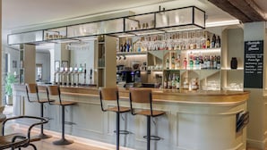 Uma área de bar com banquetas, balcão e diversos frascos e copos.