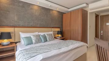 Quarto de hotel moderno com cama grande, guarda-roupa de madeira e parede com textura de pedra.