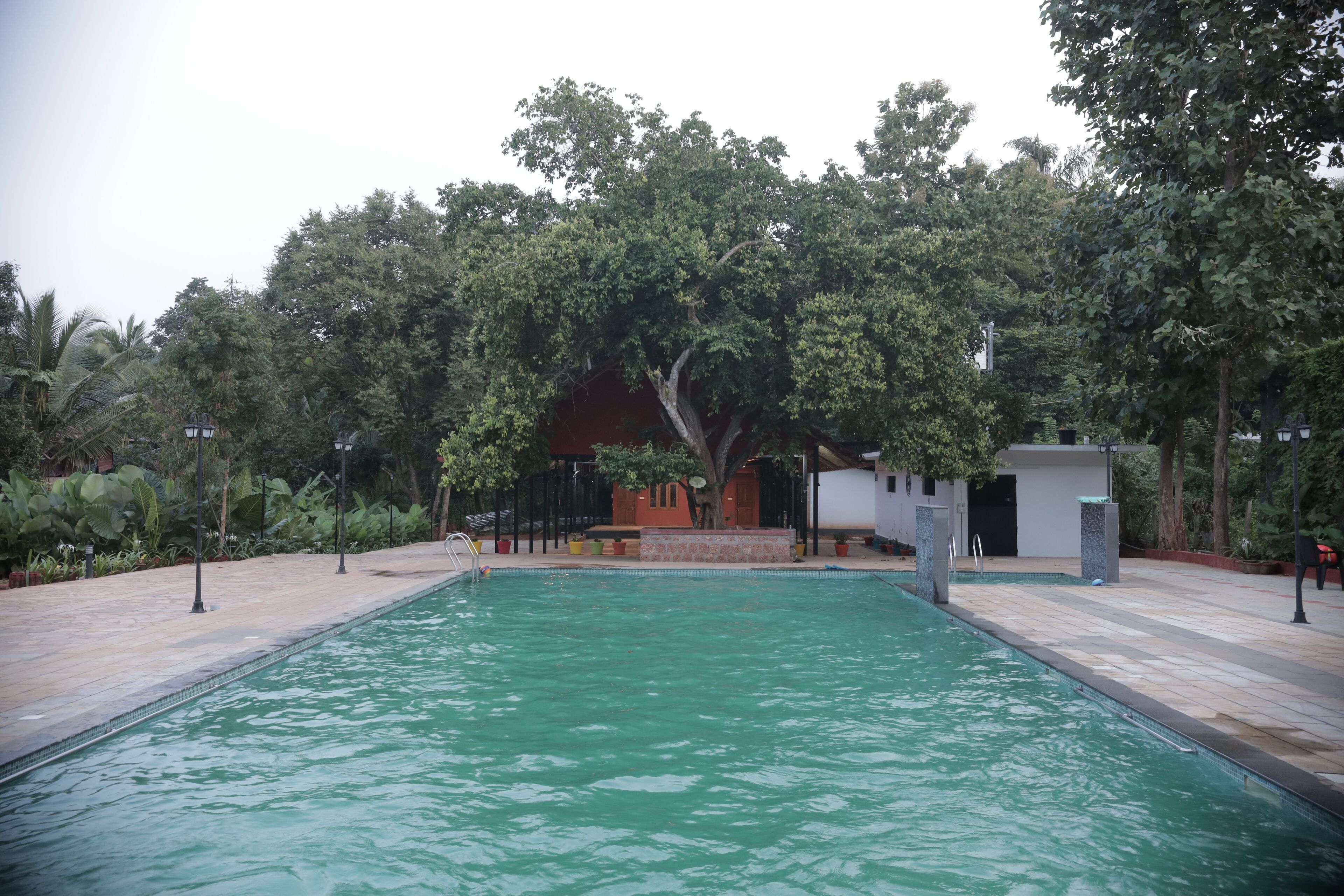 Piscina com um deck de madeira e um pequeno edifício ao fundo.