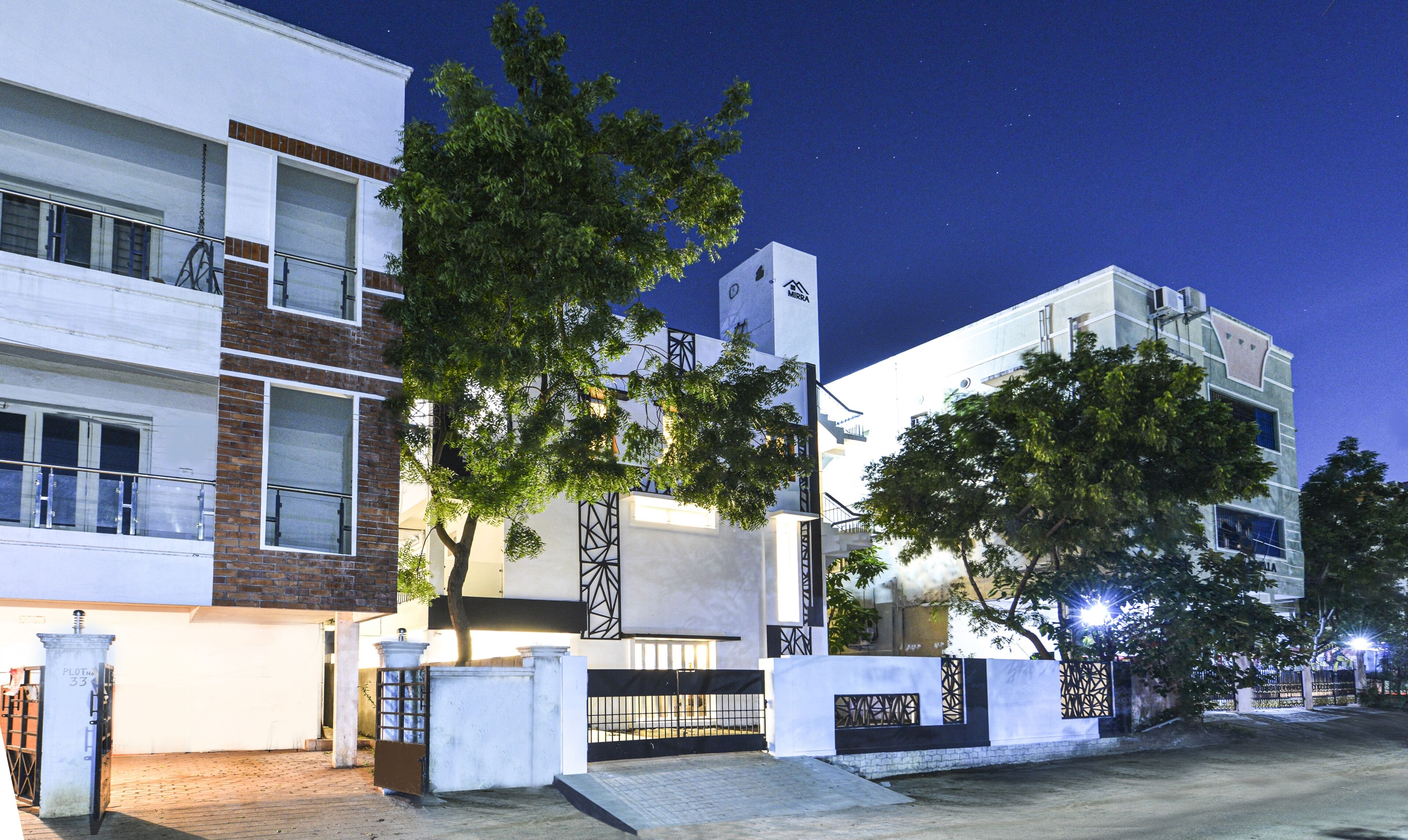 Um edifício moderno com fachada de tijolo e branco, grandes janelas e portão fechado.