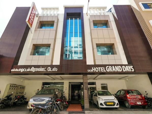 Um hotel com fachada moderna, vários espaços de estacionamento e um aviso indicando vagas.