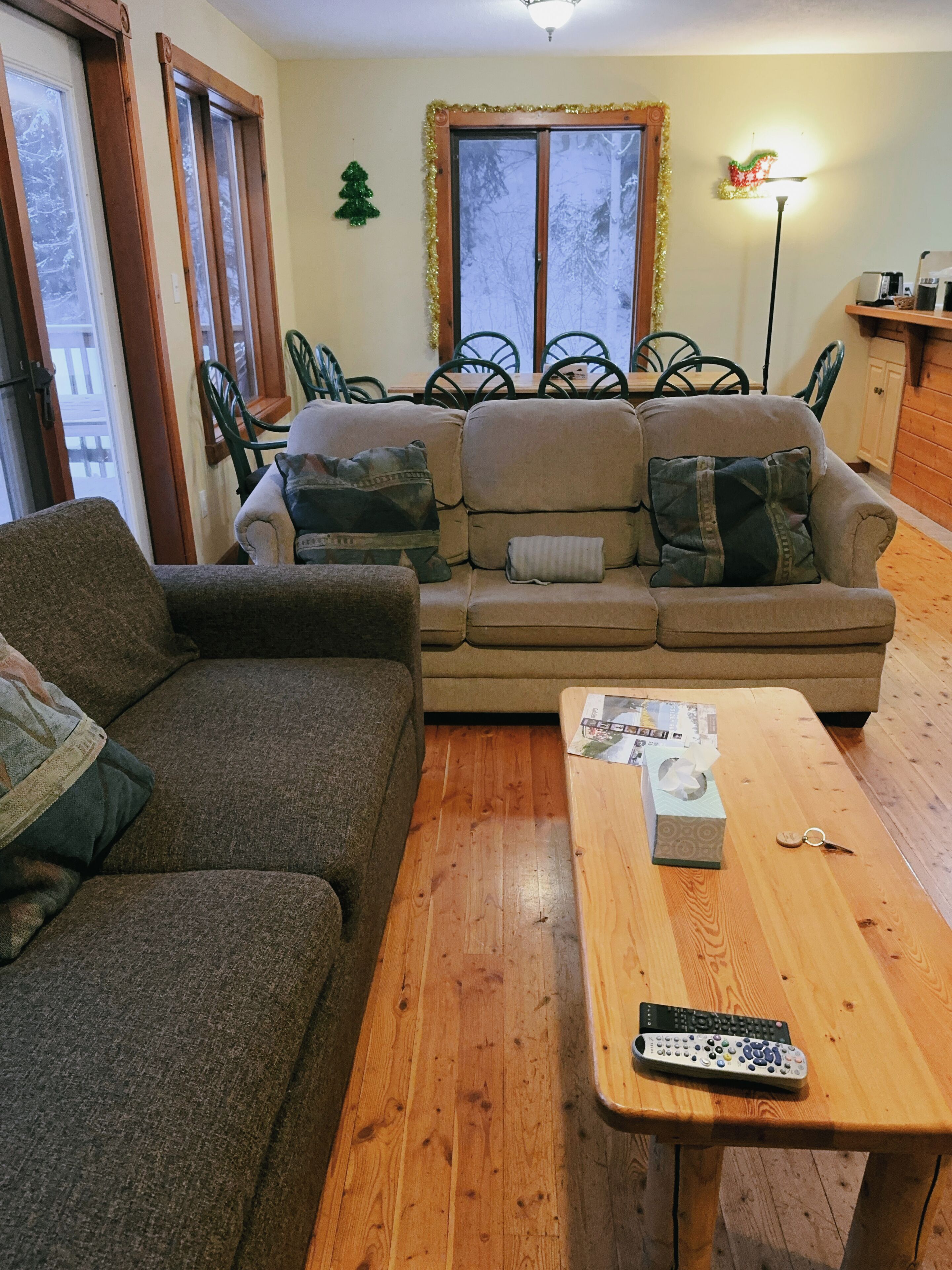 Uma sala de estar acolhedora com sofá, mesa de centro de madeira e área de jantar com cadeiras e mesa.