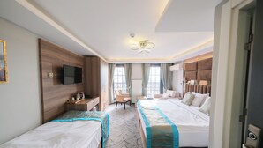 Quarto de hotel com duas camas, televisão, escrivaninha e uma cadeira.