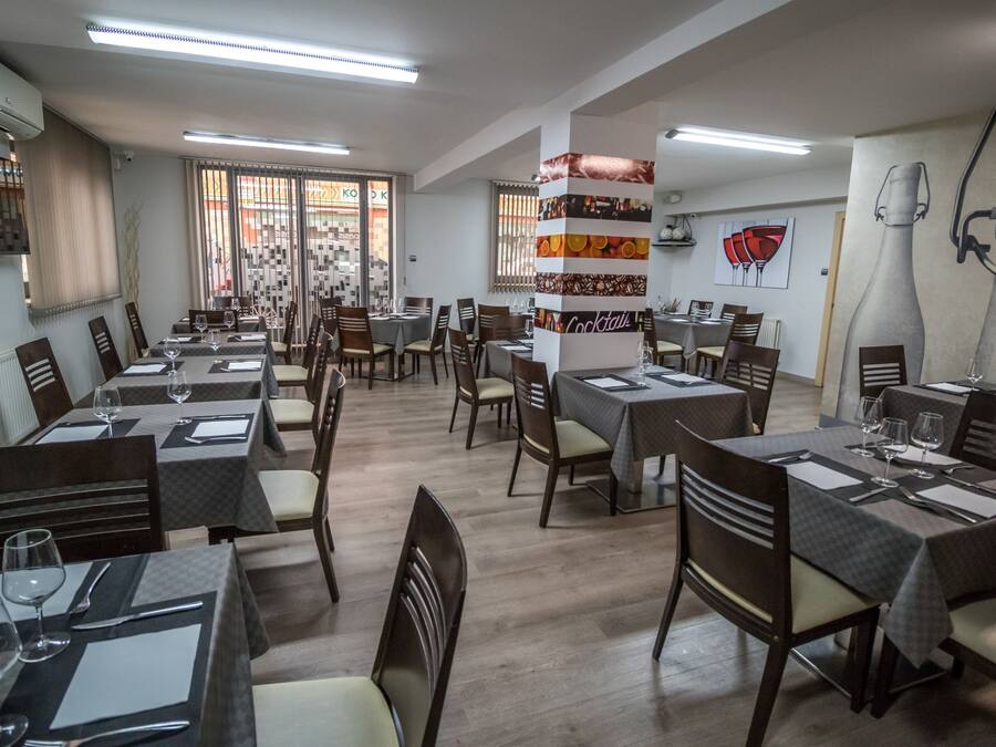 Um restaurante com várias mesas e cadeiras, dispostas num espaço amplo, com um pilar central com um design colorido.
