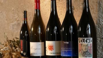 Várias garrafas de vinho dispostas numa prateleira, com um fundo rústico.