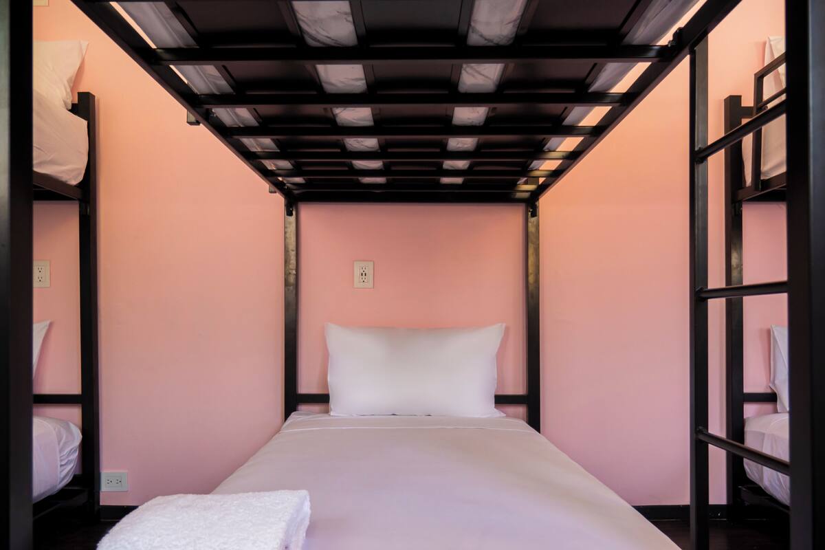 Quarto com beliche, uma cama simples, uma almofada branca e uma toalha branca.