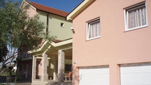 Um edifício residencial com garagem, varanda coberta e um pilar de pedra.