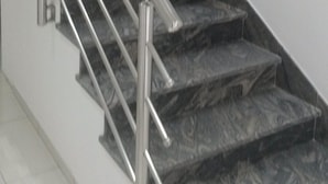 Uma escadaria com grades de metal e degraus de mármore.