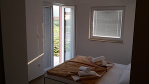 Quarto com uma cama, janela com persianas e porta para área externa.