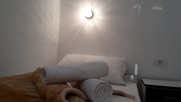 Cama bem arrumada com toalhas brancas dobradas e um cobertor marrom.