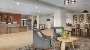 Um lobby moderno com balcão de recepção, área de estar e espaço para refeições.