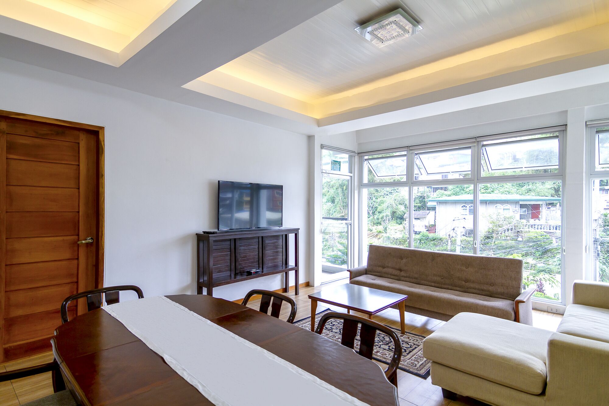 Uma sala de estar espaçosa com uma grande mesa de jantar, um sofá e uma televisão sobre um móvel.
