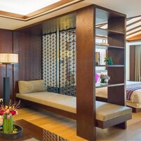 Quarto de hotel moderno com sofá embutido, divisória de madeira decorativa e estante.
