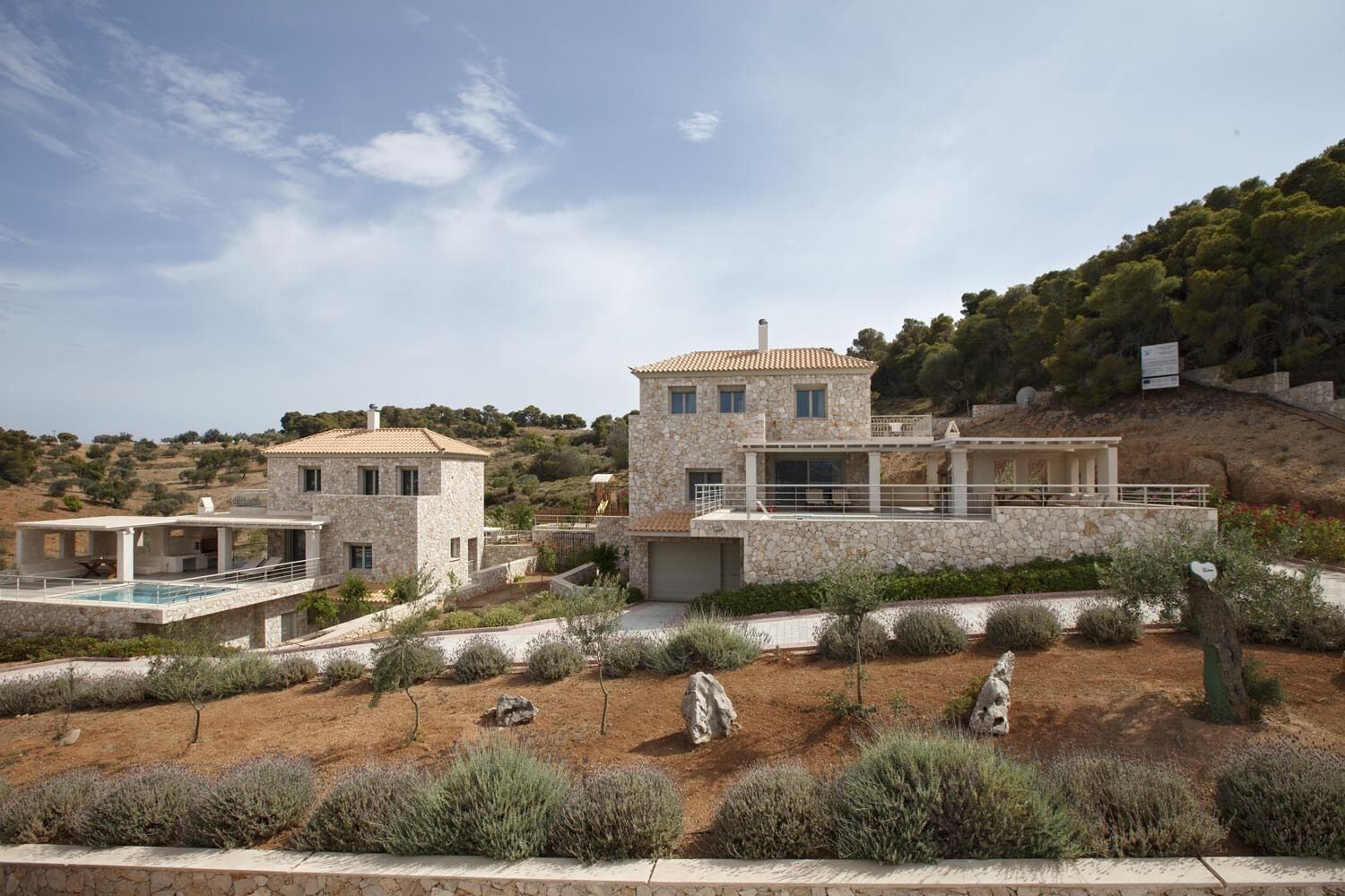 Uma villa de pedra com piscina, jardim em terraços e vista para a paisagem circundante.