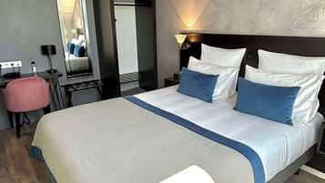 Quarto de hotel moderno com uma cama grande, mesa de cabeceira, espelho e guarda-roupa.