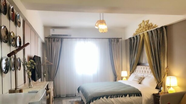 Quarto de hotel com cama, abajures, escrivaninha e uma cadeira.