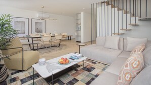Uma sala de estar moderna com um sofá, uma mesa de centro com maçãs, uma poltrona e uma escada.