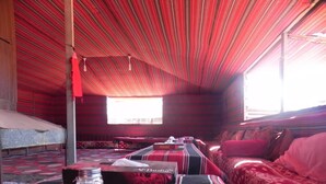 Quarto tradicional com teto listrado de vermelho, tapetes estampados e um sofá com almofadas.