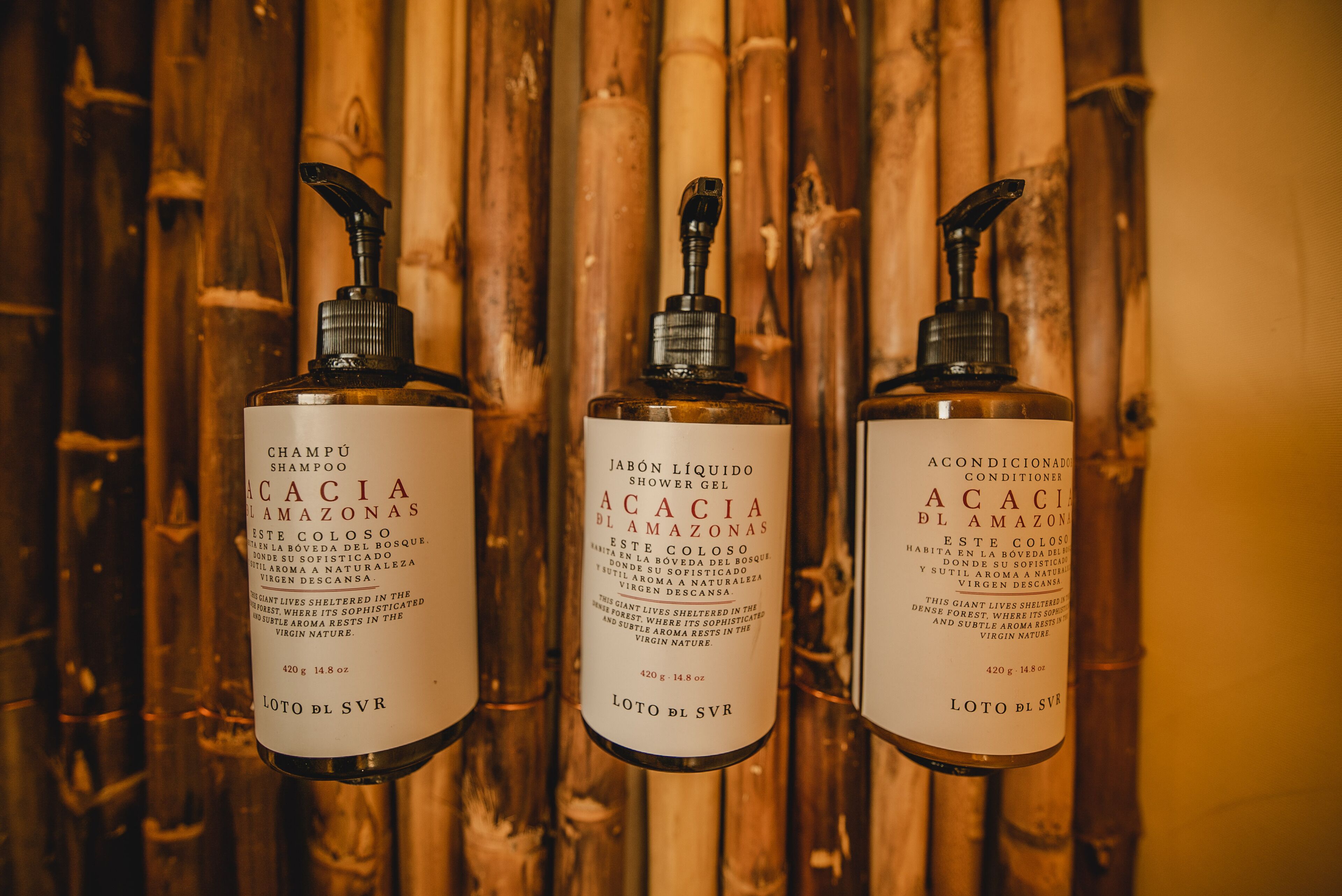 Três frascos de shampoo com fundo de bambu.