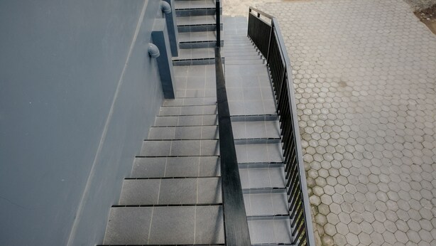 Uma escadaria com corrimão de metal que leva à entrada de um edifício.