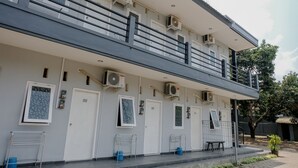 Um edifício de dois andares com várias portas e janelas, aparelhos de ar condicionado e uma varanda.