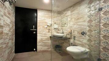 Um banheiro moderno com box de vidro, porta preta e parede revestida com padrões geométricos.