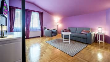 Uma sala de estar com um sofá, uma mesinha e um abajur.