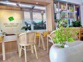 Uma área de recepção de hotel com design moderno, com balcão de recepção, área de estar com cadeiras e uma grande janela com vista para o exterior.