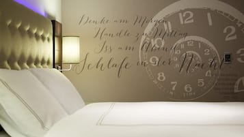 Quarto de hotel com um relógio de parede grande e uma frase motivacional.