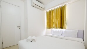 Quarto de hotel com cama, janela com cortinas, ar condicionado e porta.
