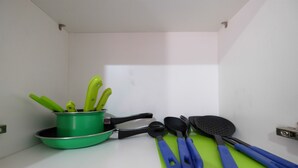 Uma área de cozinha com uma panela verde, um tábua de corte azul e diversos utensílios.