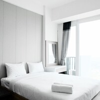 Quarto de hotel moderno com uma cama grande, mesa de cabeceira, espelho e janela com cortinas.