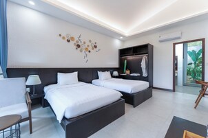 Quarto de hotel moderno com duas camas, uma escrivaninha, uma cadeira, um guarda-roupa e um objeto decorativo na parede.