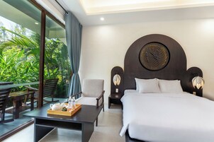 Quarto de hotel com cama, escrivaninha, cadeira e vista para o verde lá fora.