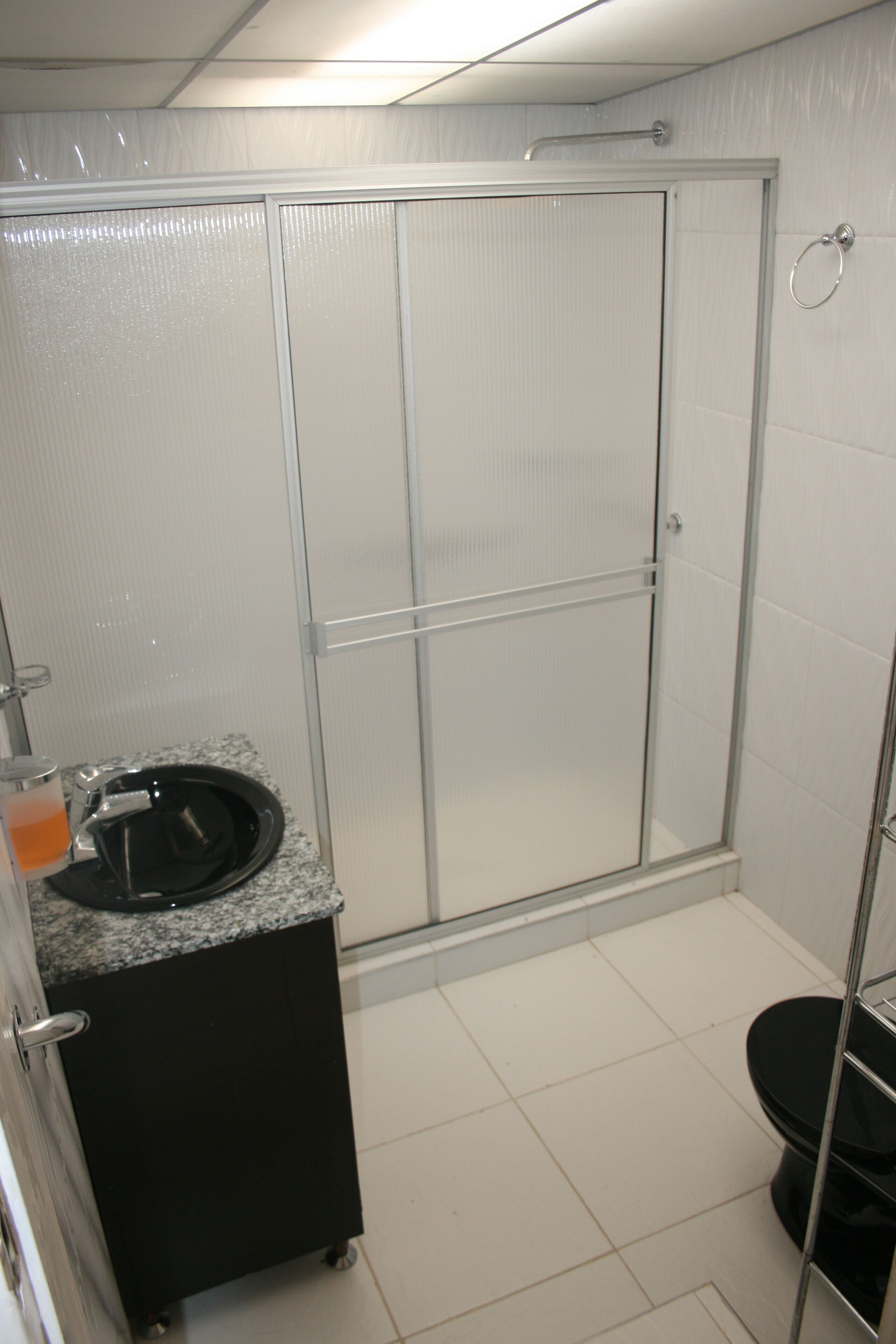 Um banheiro pequeno com chuveiro, vaso sanitário e pia.