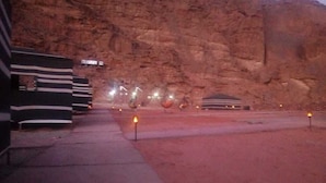 Um hotel no deserto com fachada de pedra, área de estar ao ar livre e entrada bem iluminada.