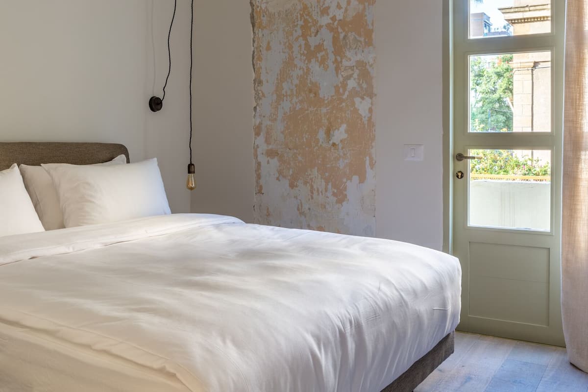 Quarto com uma cama, uma porta e vista para o exterior.