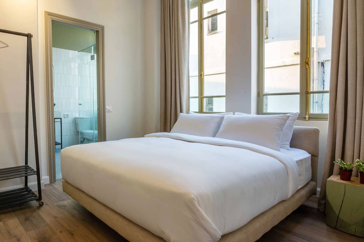 Quarto de hotel com uma cama grande, um guarda-roupa e vista para a cidade pela janela.