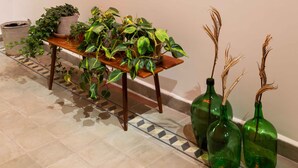 Um quarto com uma placa de neon que diz "Ramble", um banco de madeira com plantas em vasos, e três vasos verdes no chão.