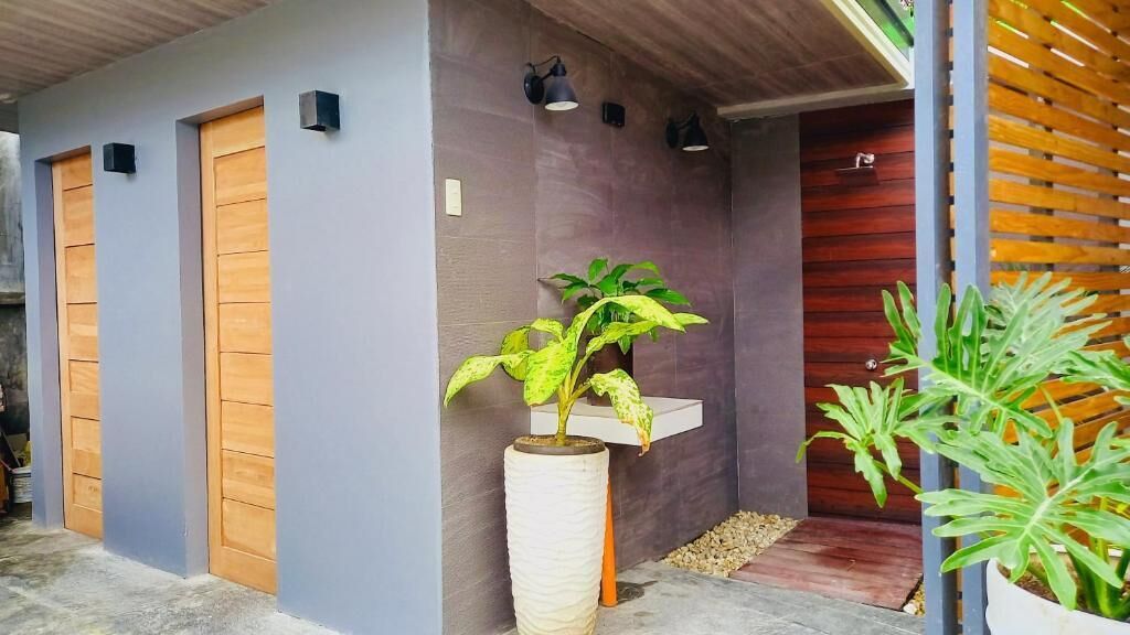 Um edifício moderno com fachada cinzenta, portas de madeira e uma planta em vaso na área de entrada.