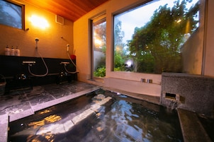 Uma área de spa com hidromassagem, uma janela com vista para vegetação e um aquecedor fixado na parede.