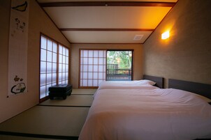 Quarto tradicional japonês com piso de tatame, futon, portas deslizantes shoji e vista para o exterior.