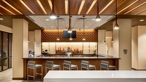 Uma área de bar moderna com teto de madeira, banquetas e um balcão longo.